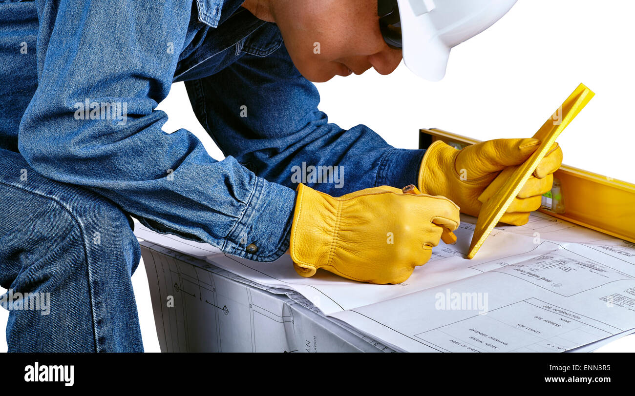Man wearing hardhat leaning over table looking at blueprints with ...