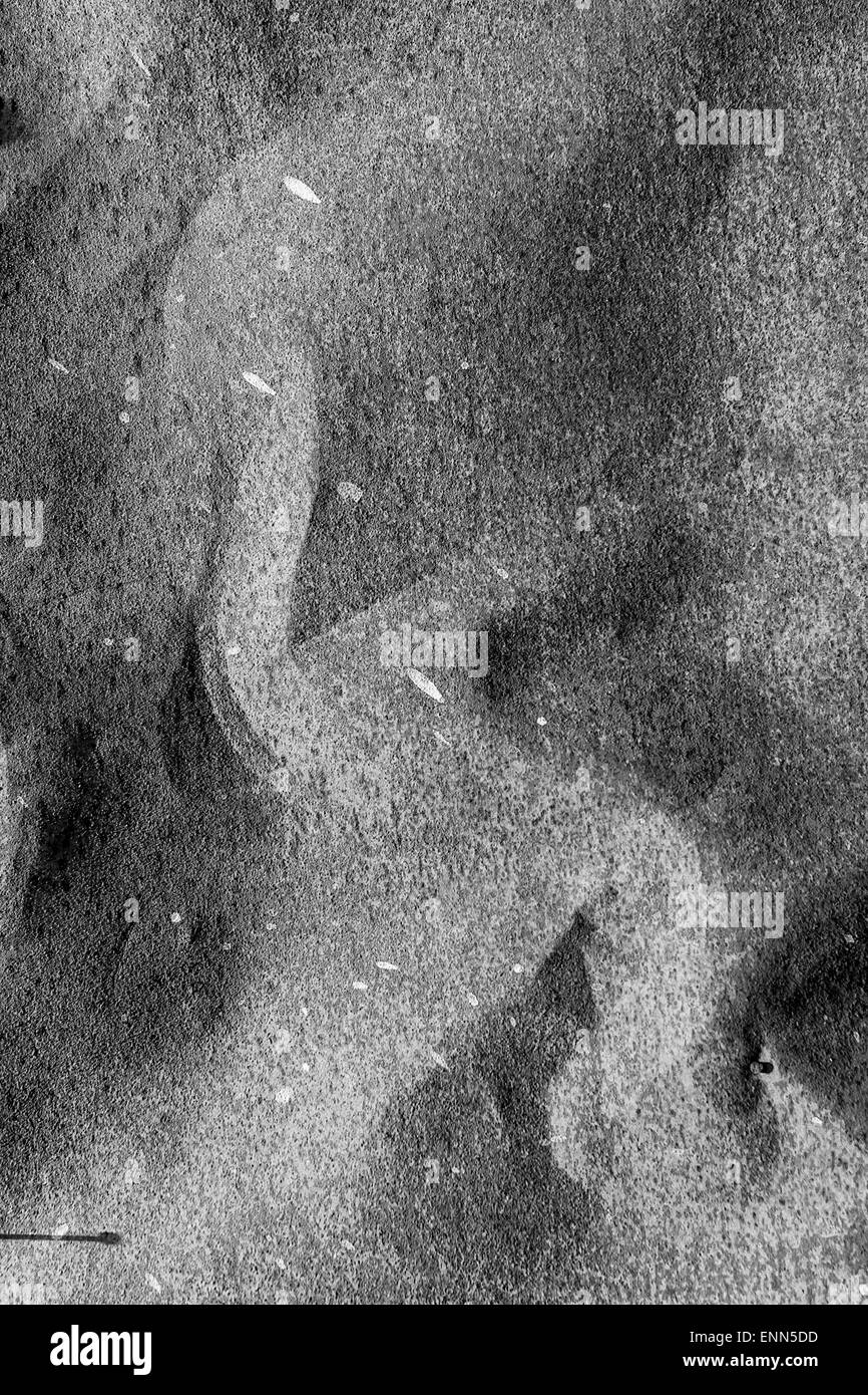 Beaten buckled metal with paint splashes and shadows in black and white ...