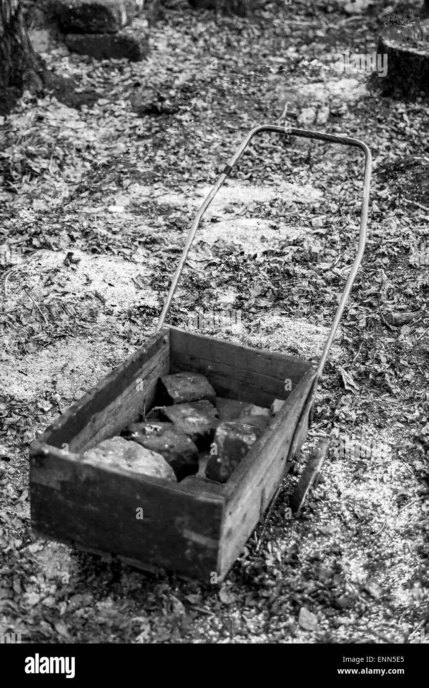 Antique wheelbarrow in a forest setting with a pile of bricks and rocks ...