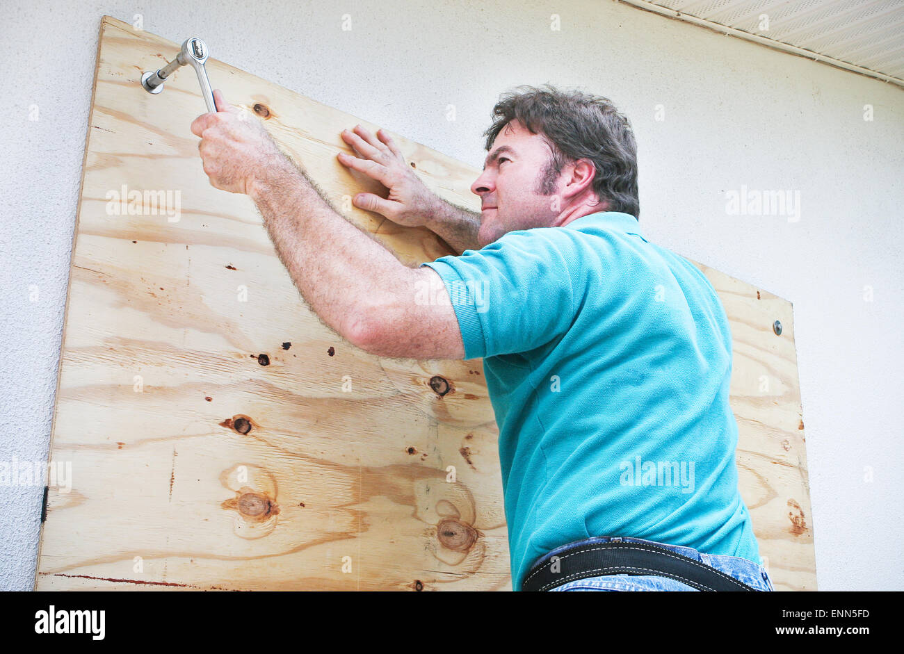 Man boarding up the windows on his home to prepare for a hurricane or ...