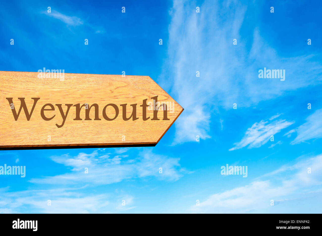 Wooden arrow sign pointing destination WEYMOUTH, ENGLAND against clear ...