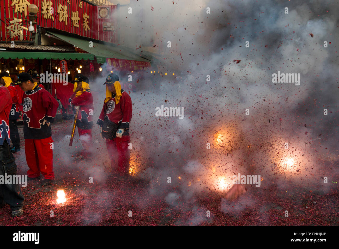 Palanquin bearers turn their backs on a pile of firecrackers in a ...