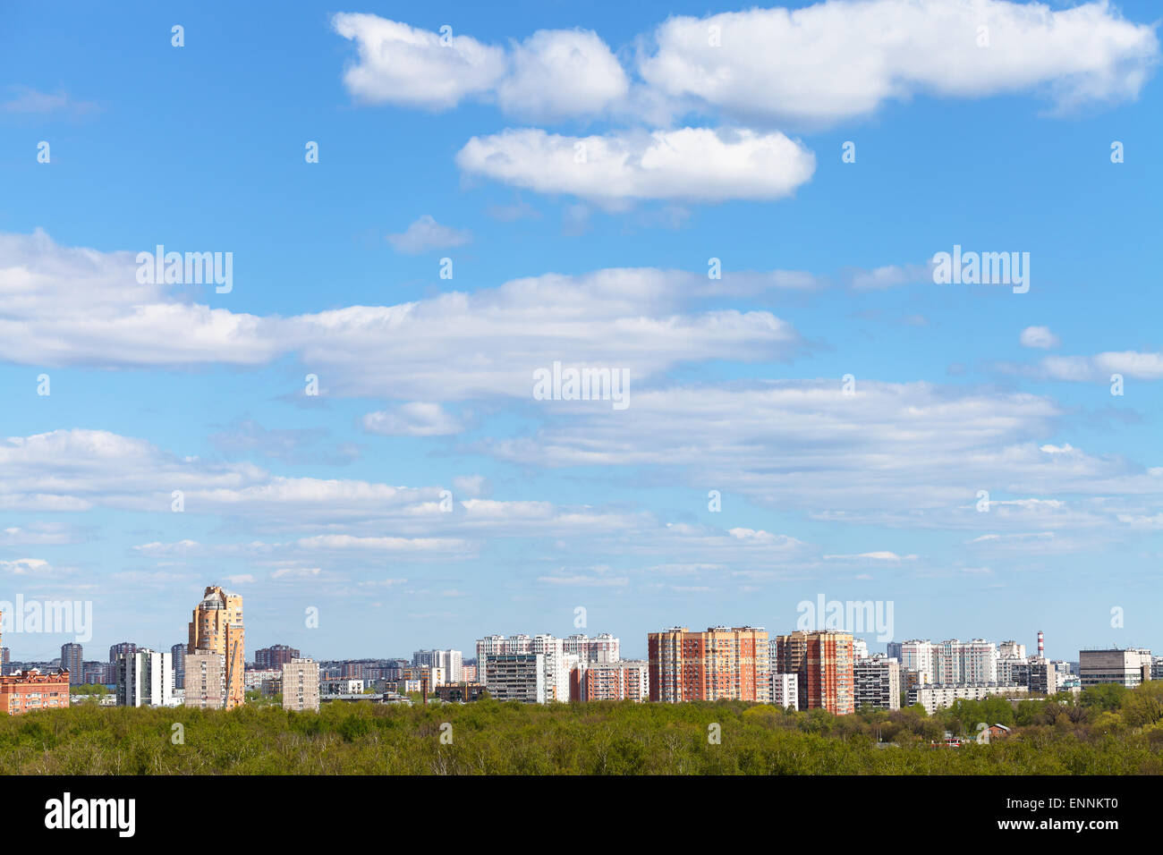 blue spring sky with white clouds over city and green woods in sunny ...