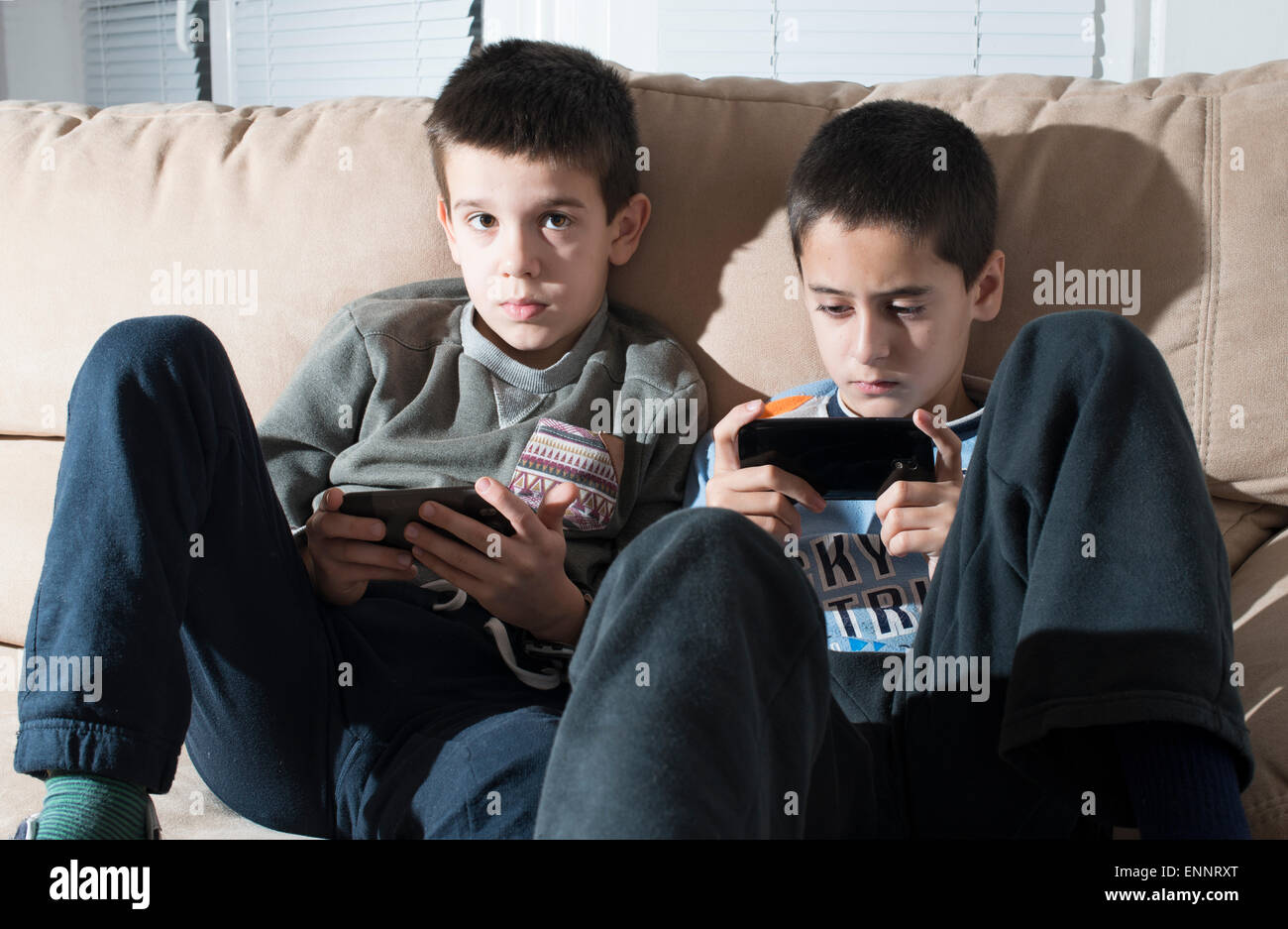 Children playing with their smartphones. Two boys with mobile phones ...