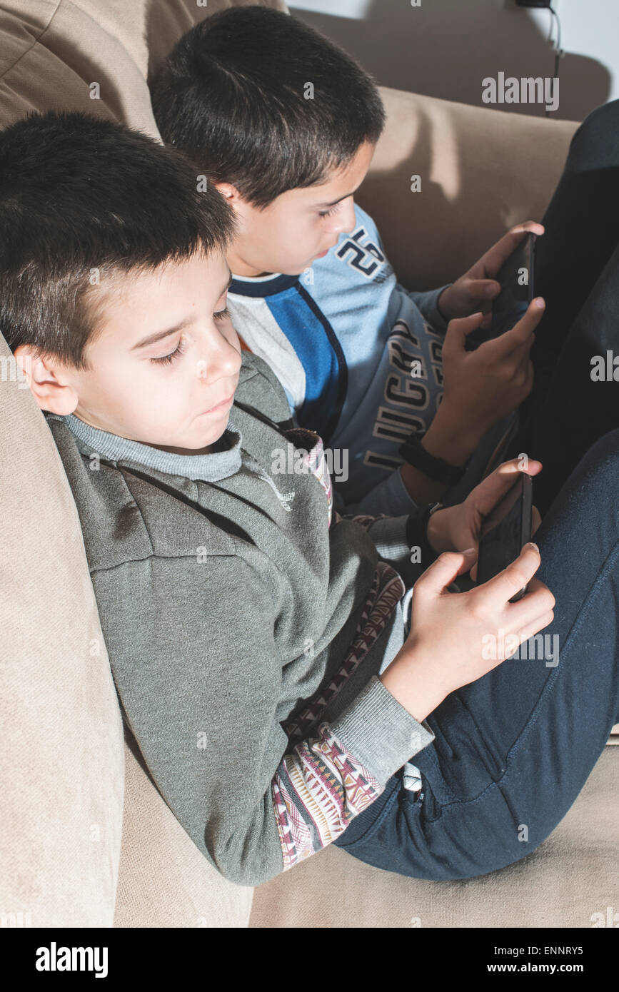 Children playing with their smartphones. Two boys with mobile phones ...