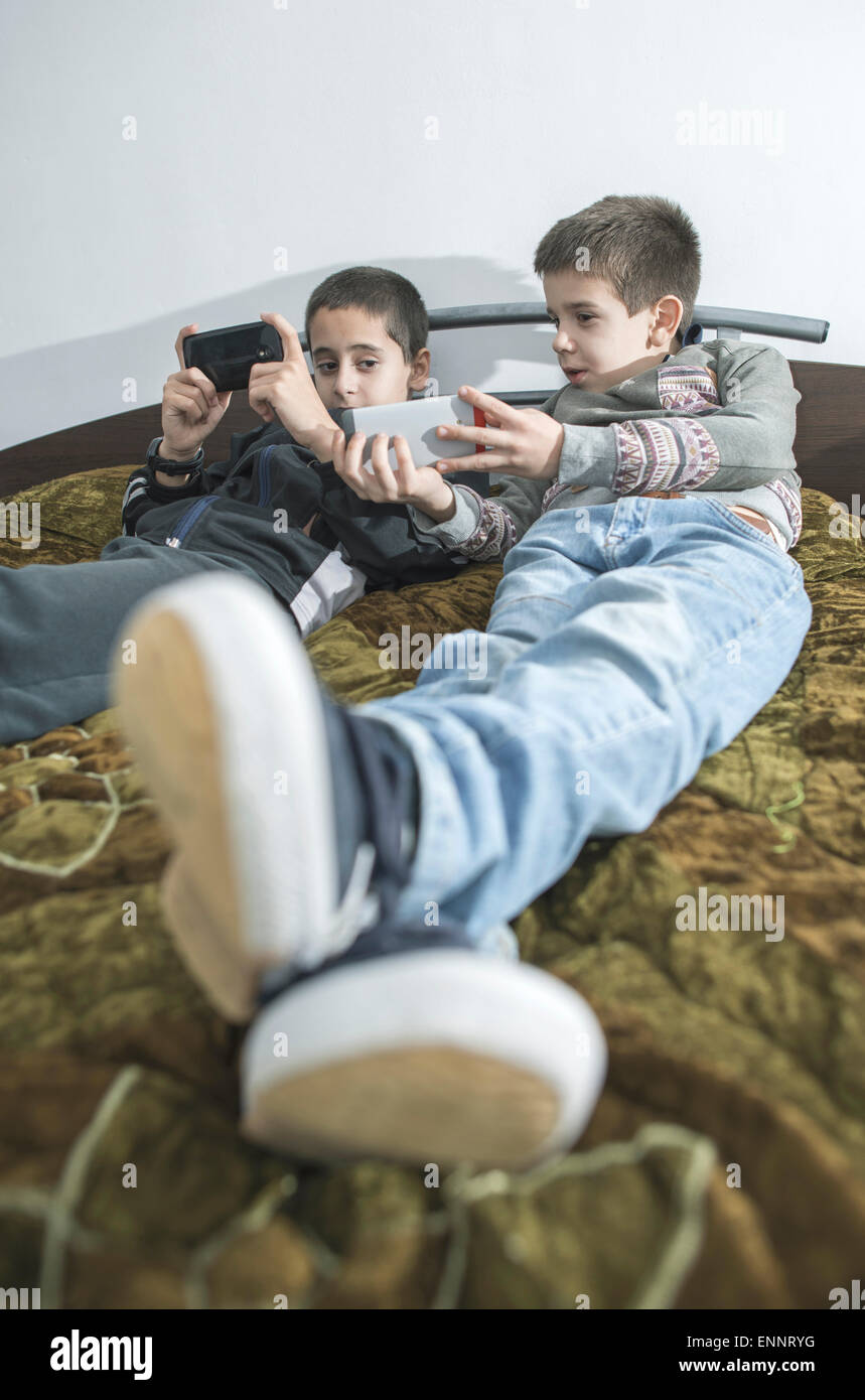 Children playing with their smartphones. Two boys with mobile phones ...