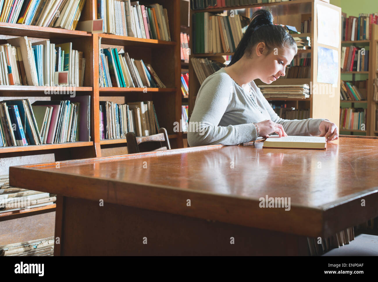 Student girl in a library. Looking at book Stock Photo - Alamy