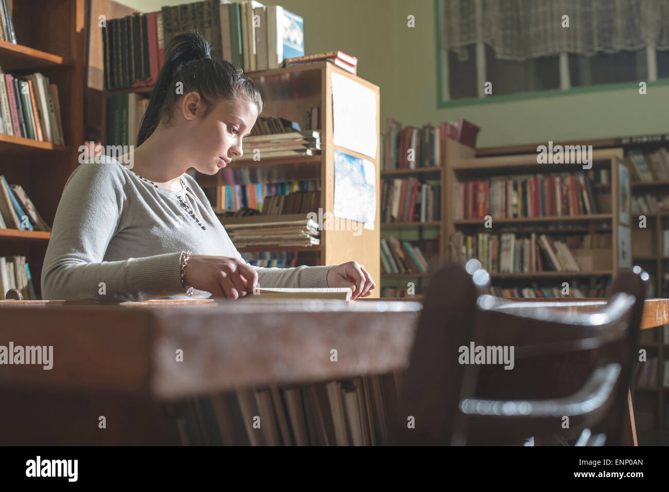 Student girl in a library. Looking at book Stock Photo - Alamy