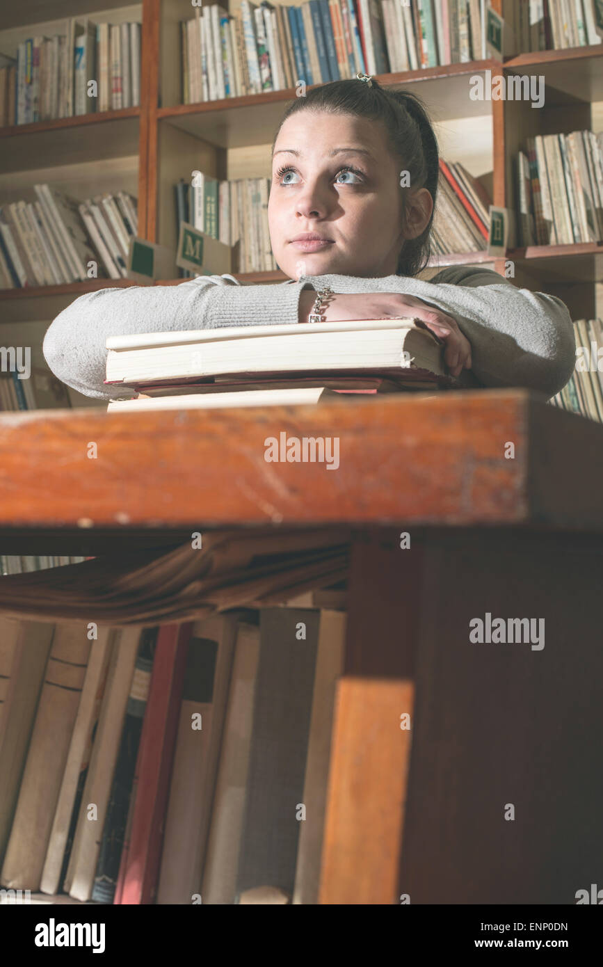 Student girl in a library. Looking at book Stock Photo - Alamy