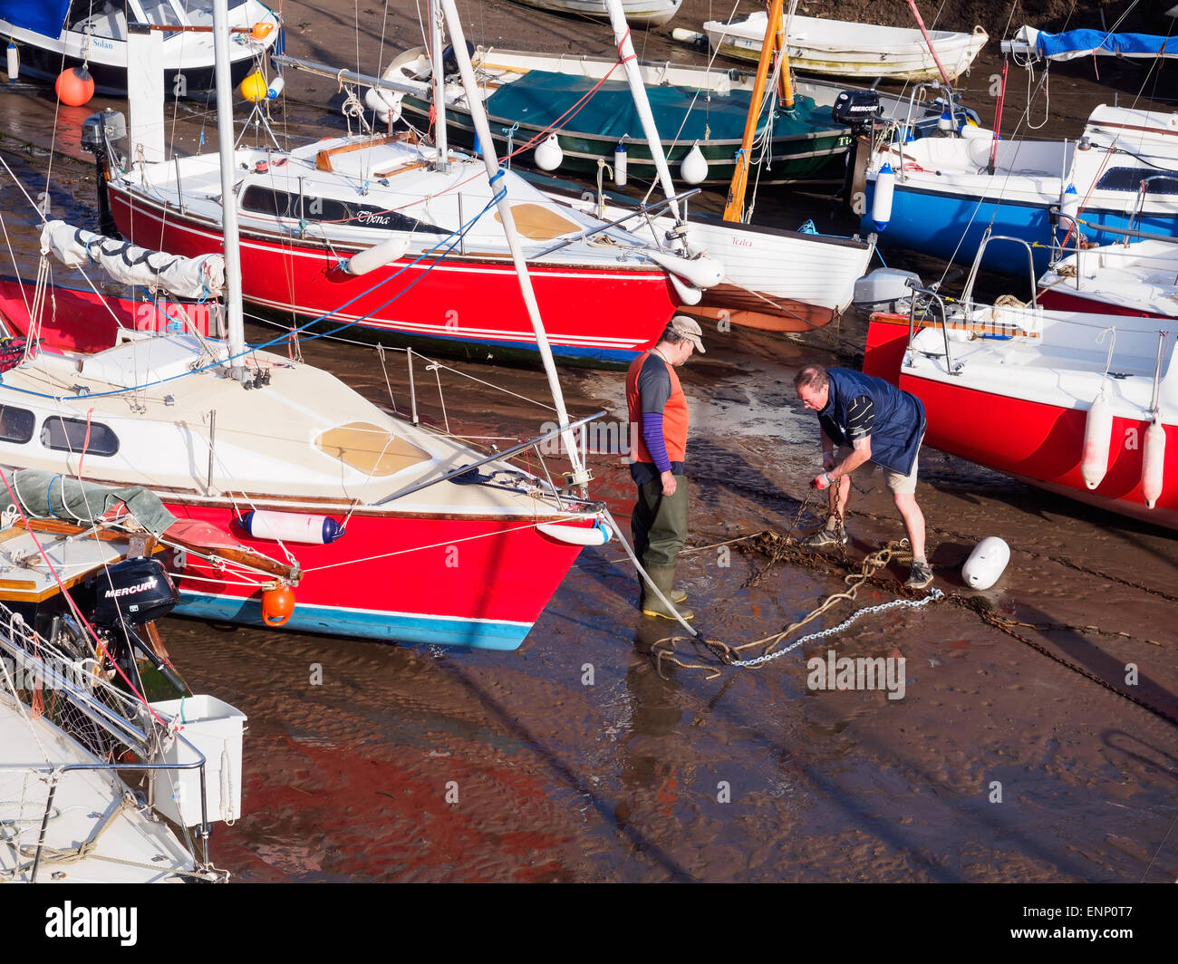 Men working on a boat mooring at low tide in the harbour at North ...