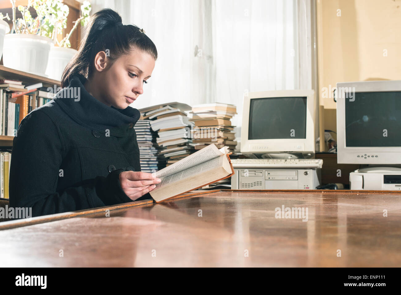Student girl in a library. Looking at book Stock Photo - Alamy