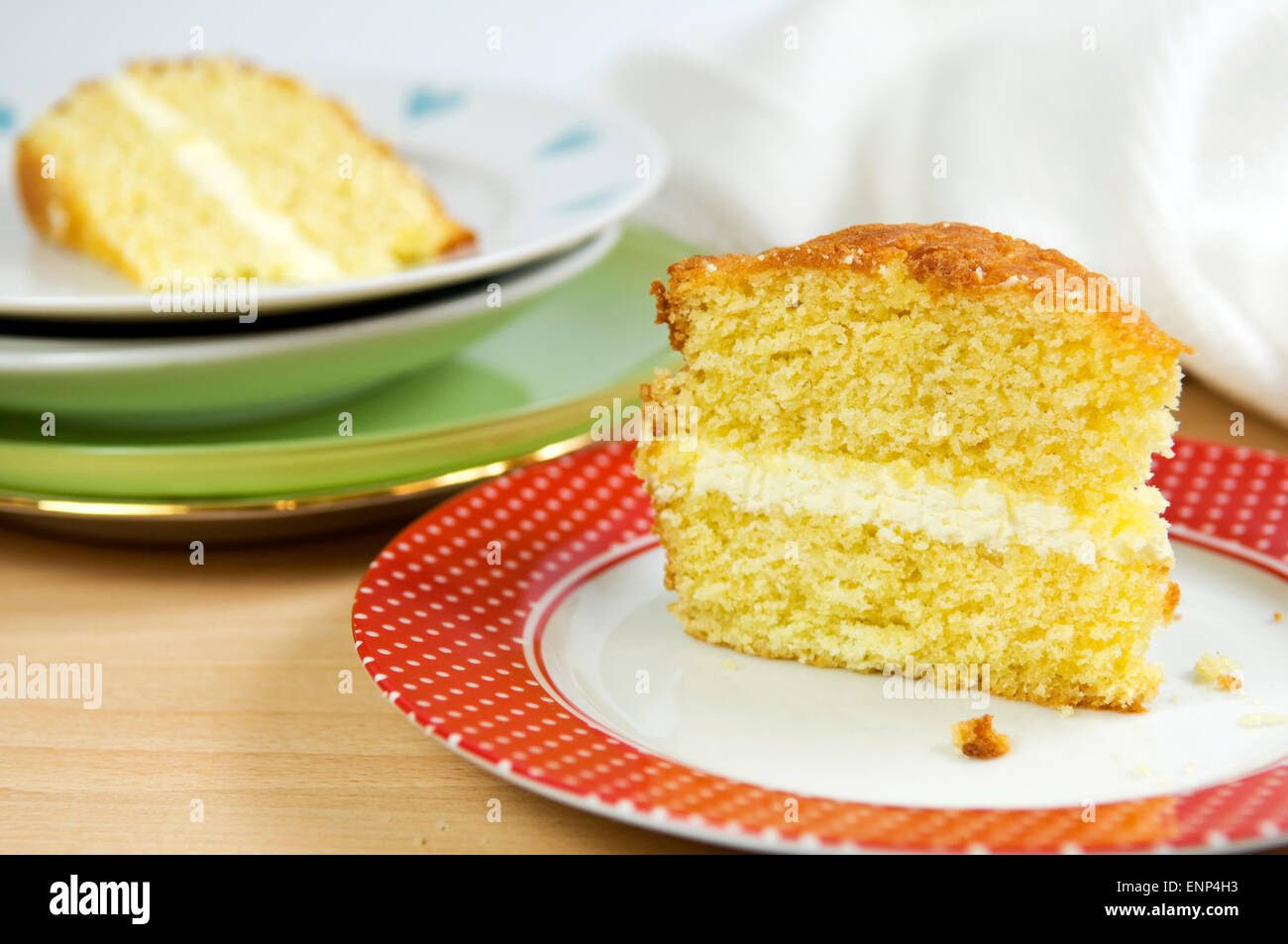 Sponge cake with a buttercream icing filling on red and white plate ...