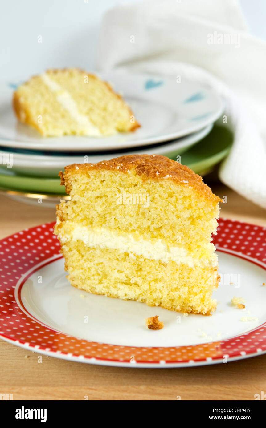Sponge cake with a buttercream icing filling on red and white plate ...