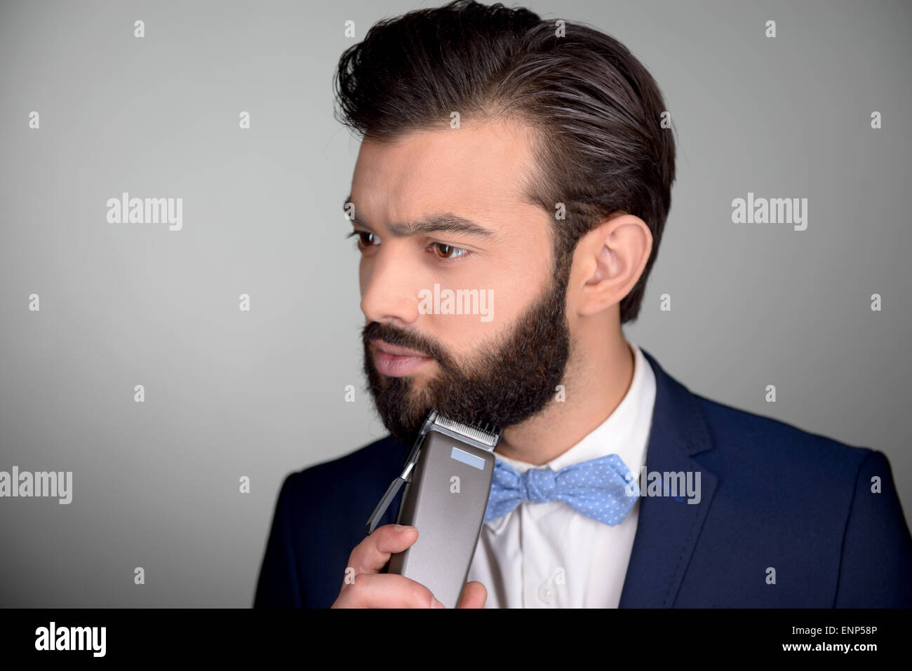 Handsome man with beard using electric shaver Stock Photo - Alamy