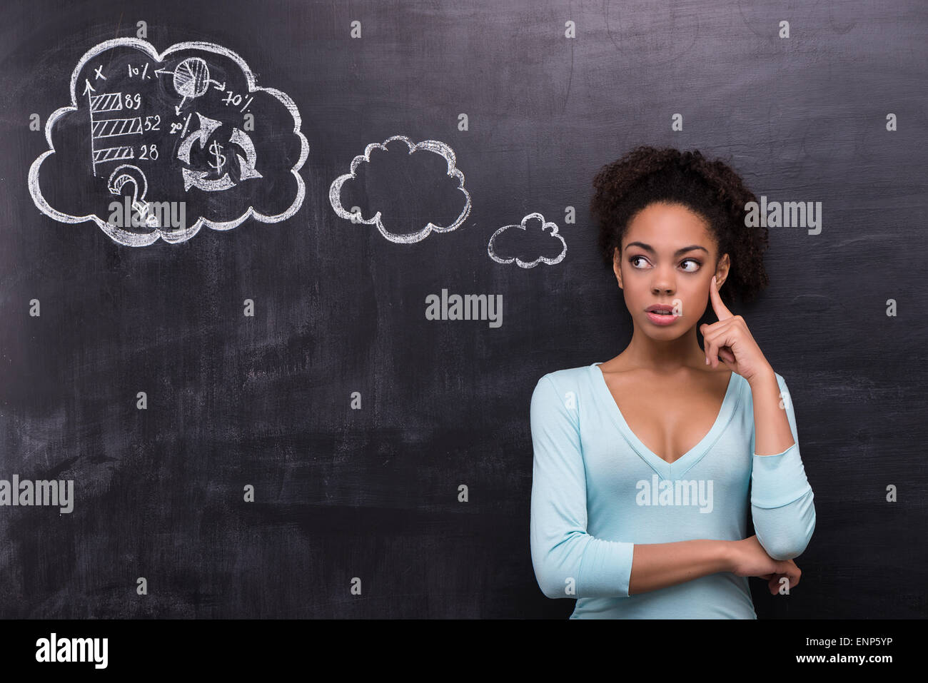 Thoughtful afro-american woman trying to solve a problem on chalkboard ...