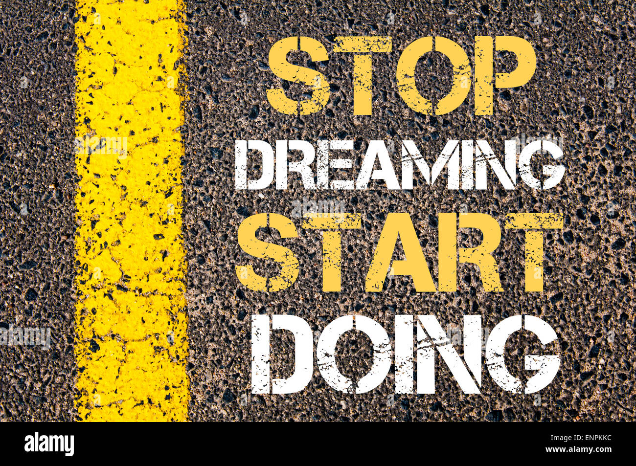 Stop dreaming start doing motivational quote. Yellow paint line on the road against asphalt ...
