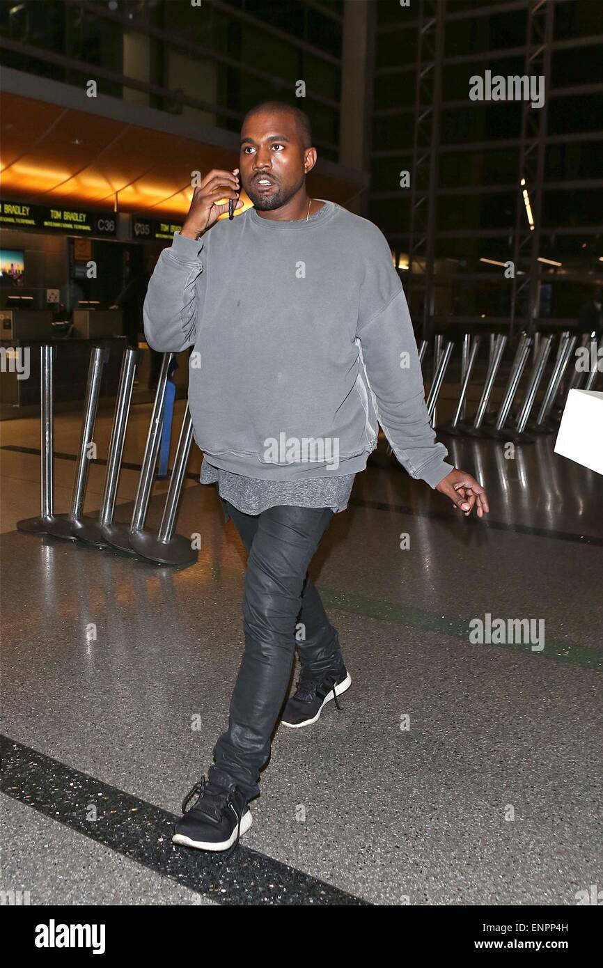 Kanye West talks on his cell phone as he departs from Los Angeles ...