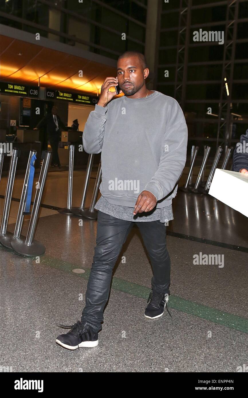 Kanye West talks on his cell phone as he departs from Los Angeles ...