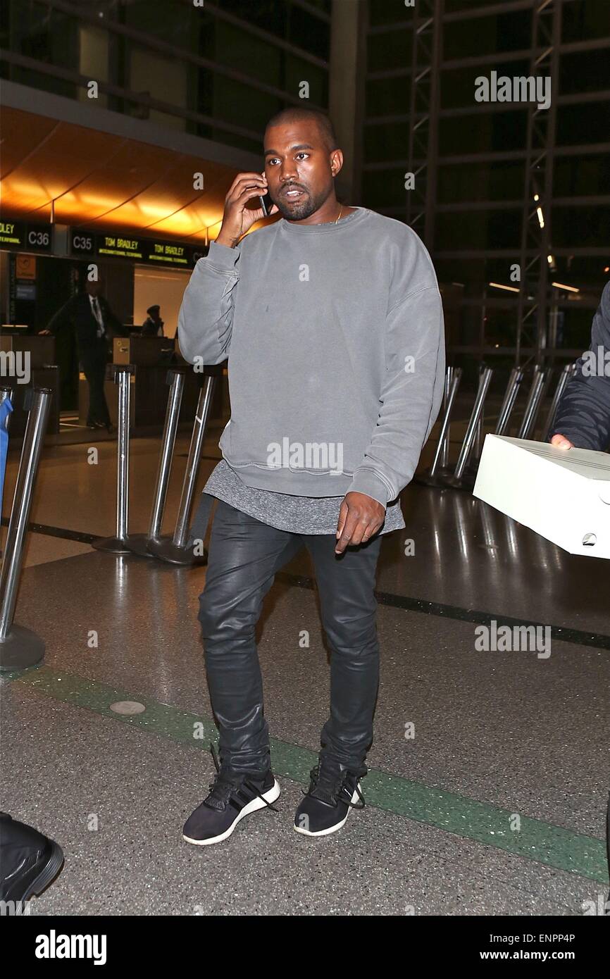 Kanye West talks on his cell phone as he departs from Los Angeles ...