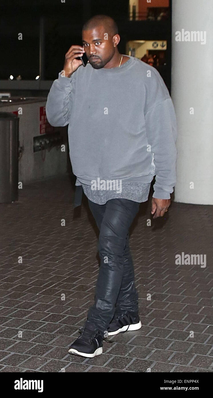 Kanye West talks on his cell phone as he departs from Los Angeles ...
