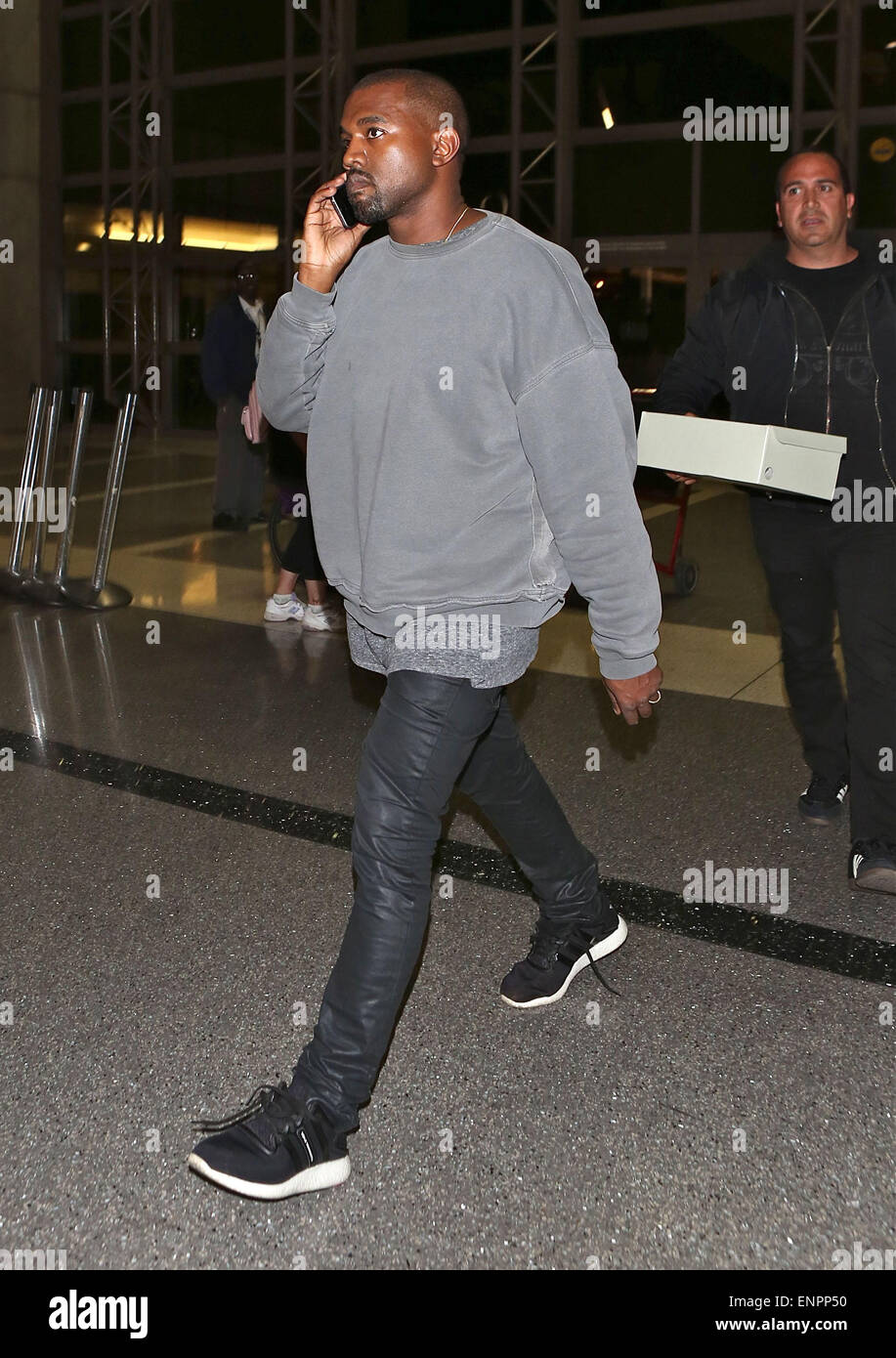 Kanye West talks on his cell phone as he departs from Los Angeles ...