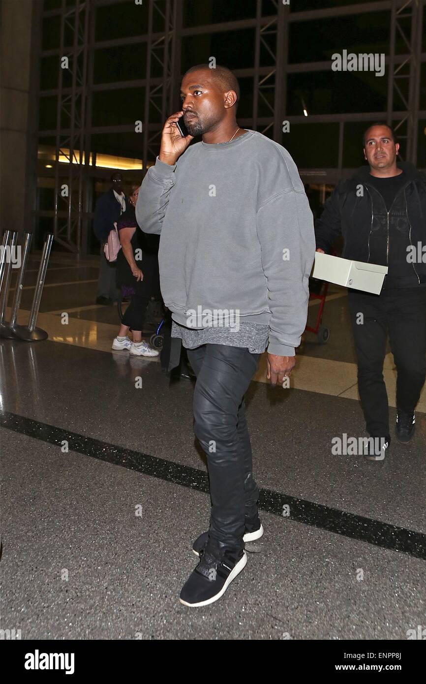 Kanye West talks on his cell phone as he departs from Los Angeles ...