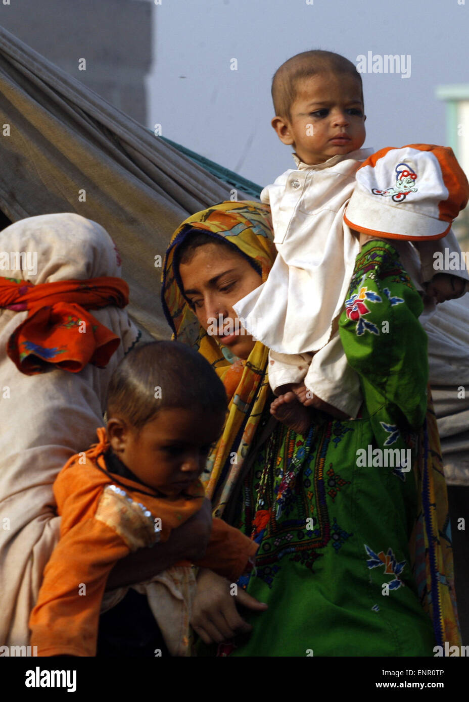Peshawar. 10th May, 2015. A Pakistani mother carries her children as ...