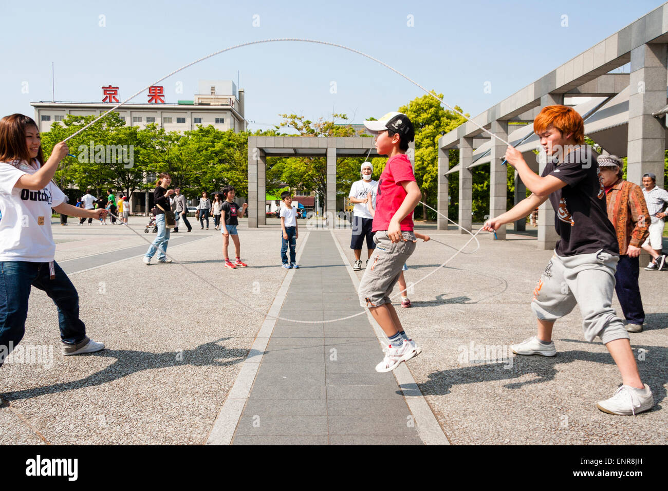 Side view of a young Japanese boy jumping in skipping contest with girl ...