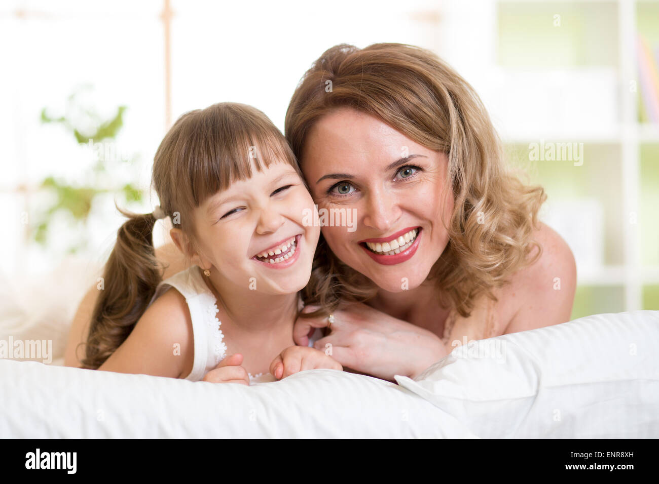 Portrait of a joyful mother and her daughter lying on bed in bedroom Stock Photo - Alamy