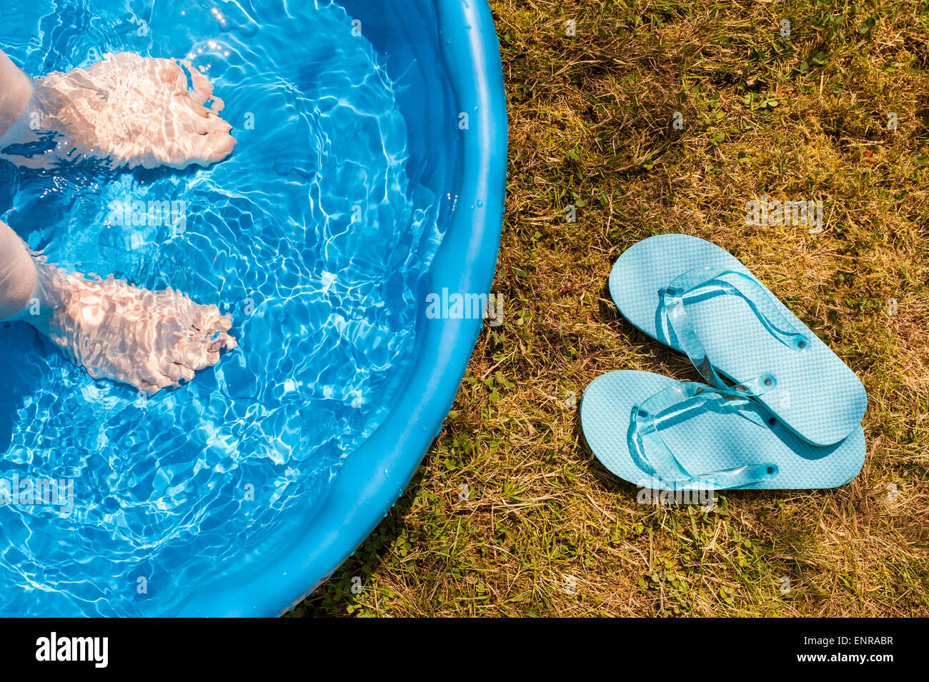 Woman's feet in pool with motion and flip flops along side of pool ...
