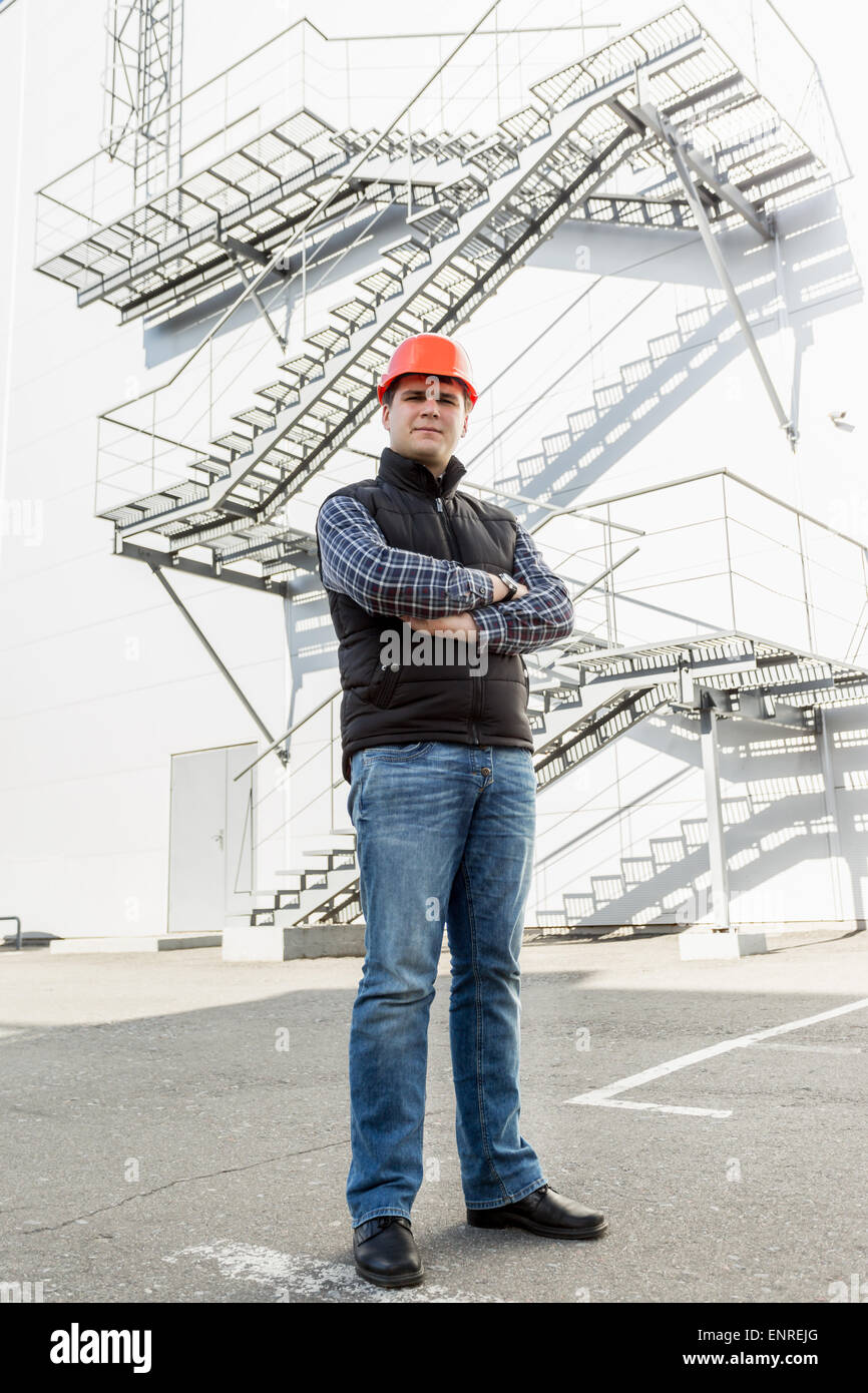 Full length portrait of architect posing against metal construction ...