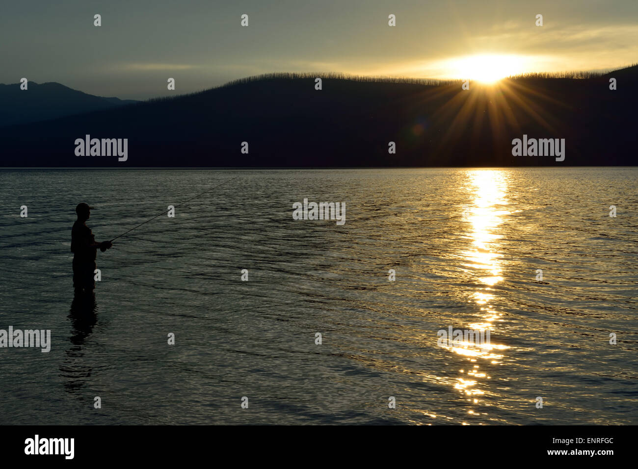 fisherman fishing in McDonald lake in Glacier National Park, Montana at sunset in summer Stock ...
