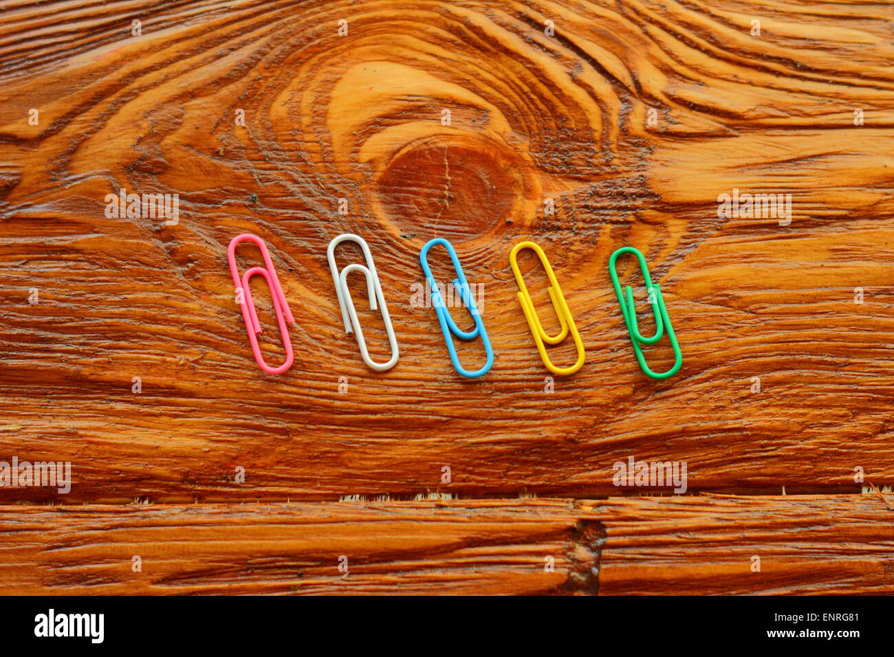 on a wooden board four paper clips Stock Photo - Alamy