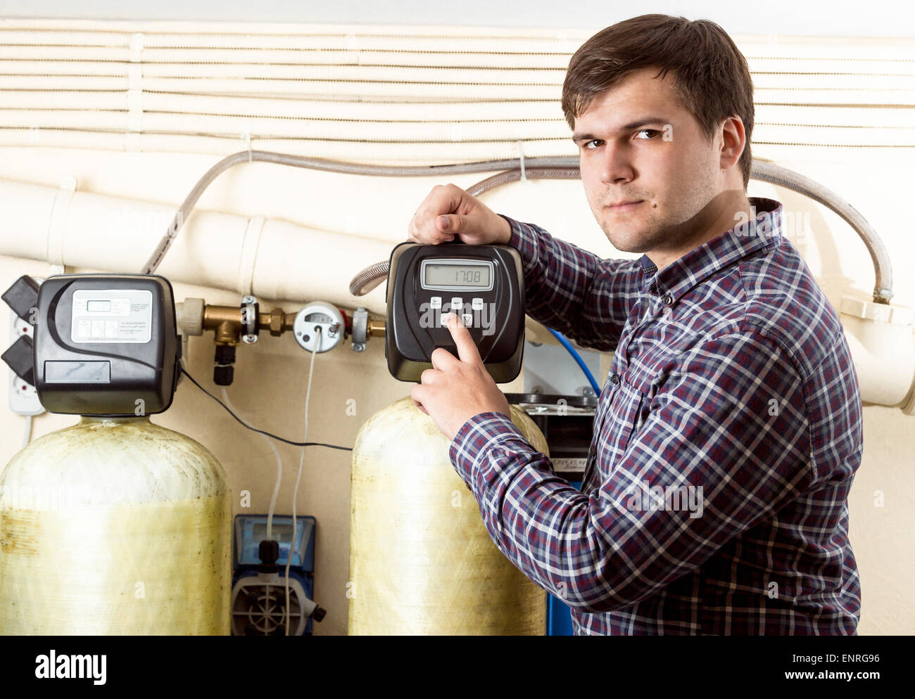 Portrait of young engineer pressing button on control panel with ...