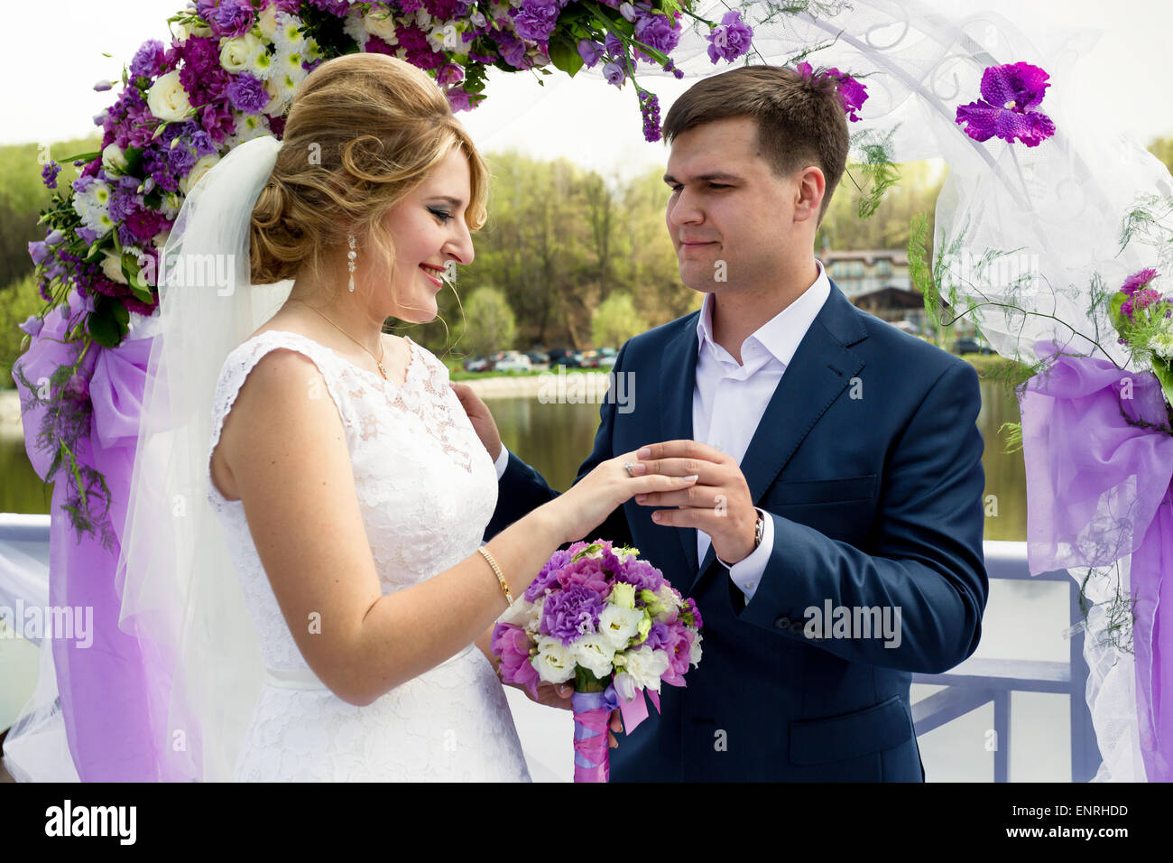 Portrait of handsome smiling groom putting ring on brides hand Stock ...