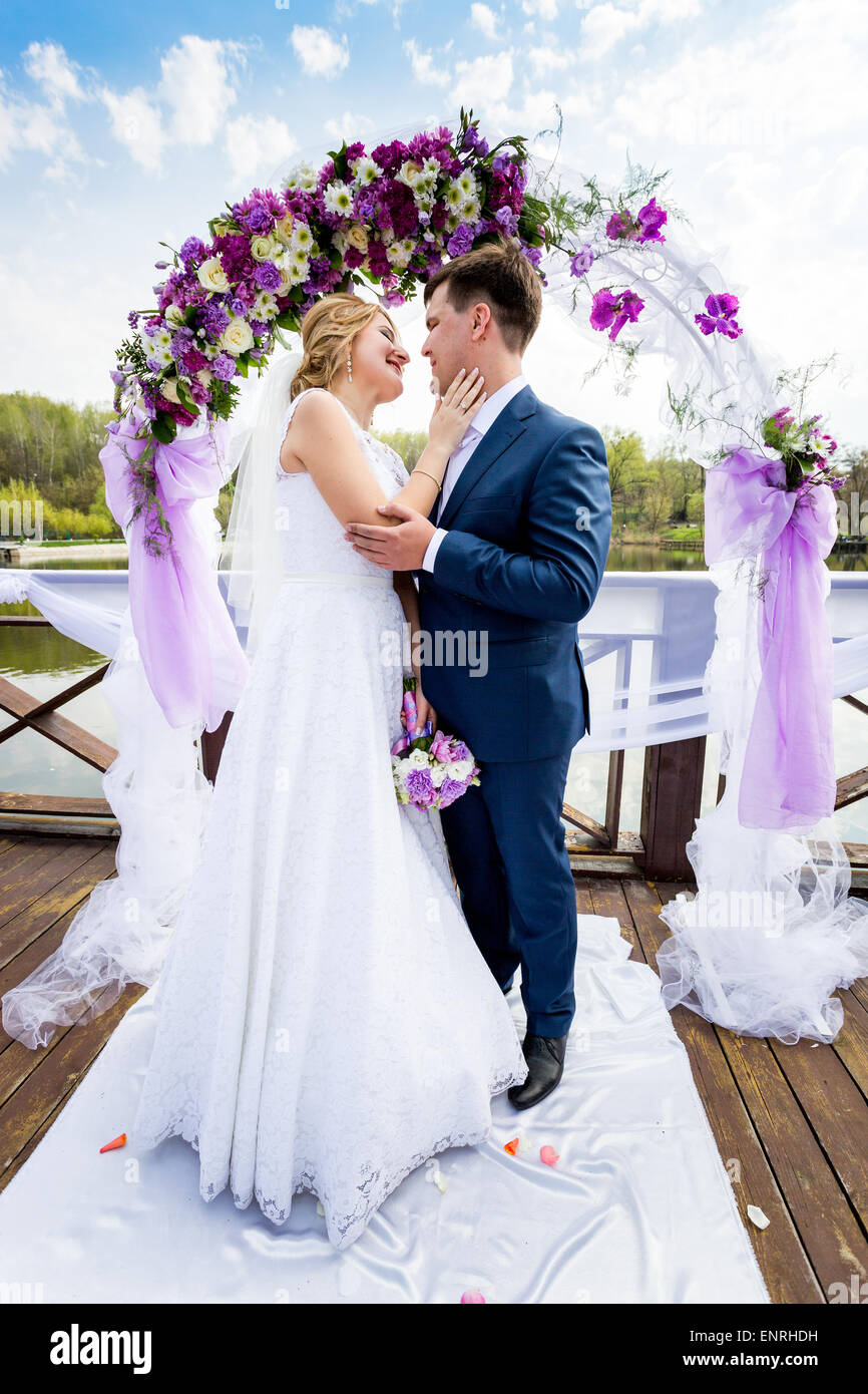 Beautiful bride and groom hugging under decorated flower arch Stock ...