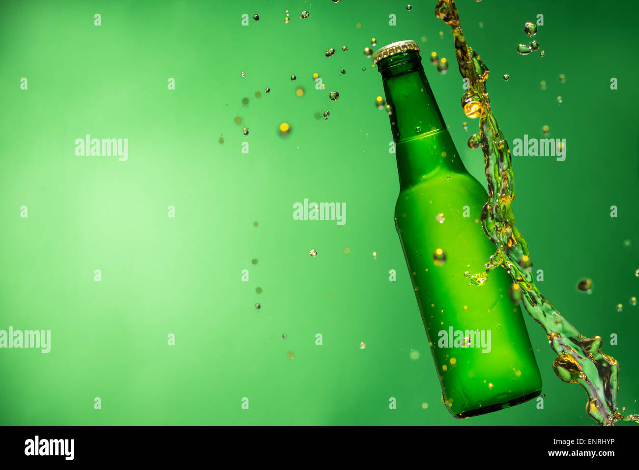 Bottle of beer with splash around on green background Stock Photo - Alamy