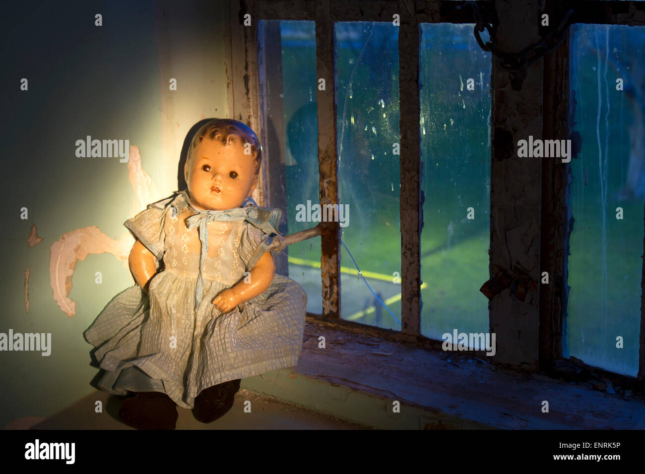 Babydoll in state of deterioration sitting in decaying building window ...
