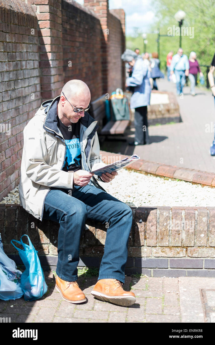 man sat on a wall reading in the sunshine Stock Photo - Alamy