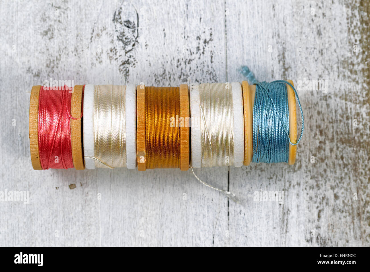 Top view of colorful spools of thread on rustic white wood. Layout in ...