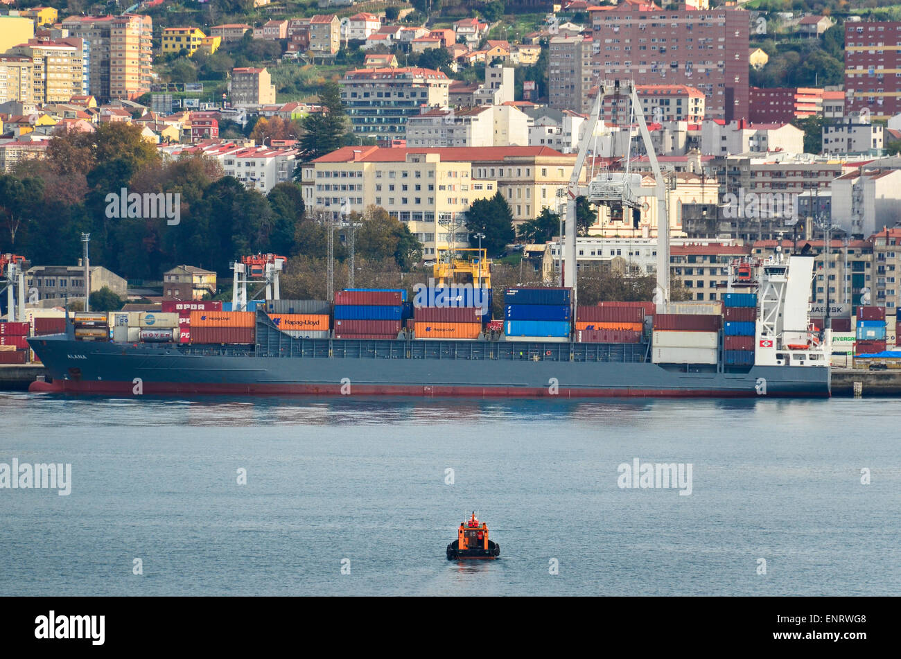Small tugboat going towards a large container ship at the container ...