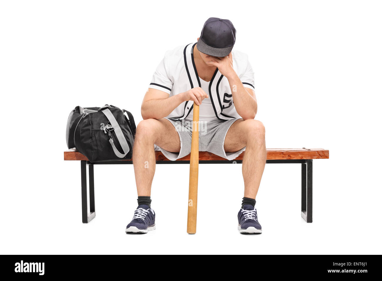 Sad young baseball player sitting on a bench and contemplating with his ...