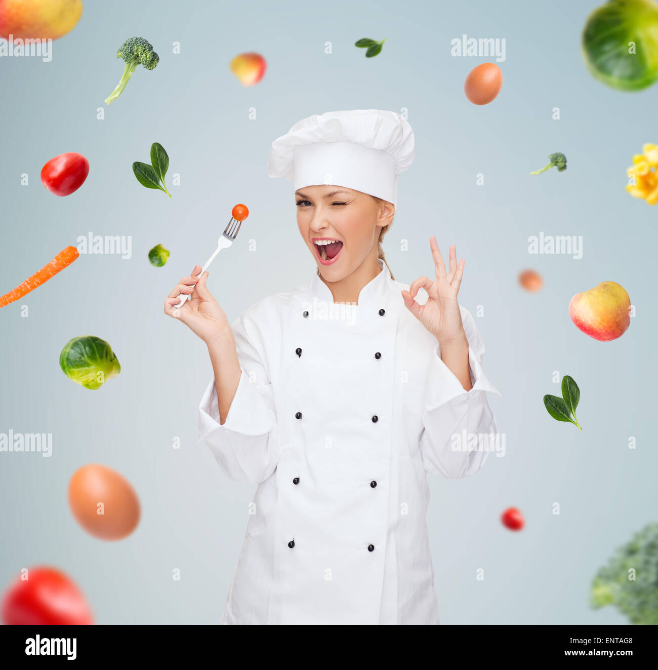 smiling female chef with fork and tomato Stock Photo - Alamy