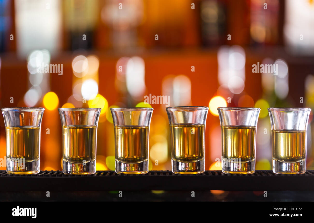 Variation of hard alcoholic shots served on bar counter. Blur bottles ...