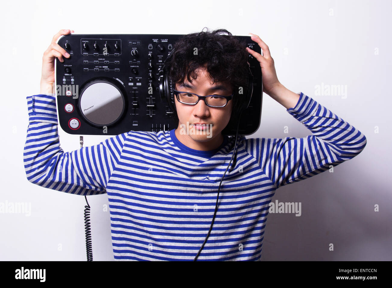 Asian young man looking in-camera holding digital turn table wearing ...