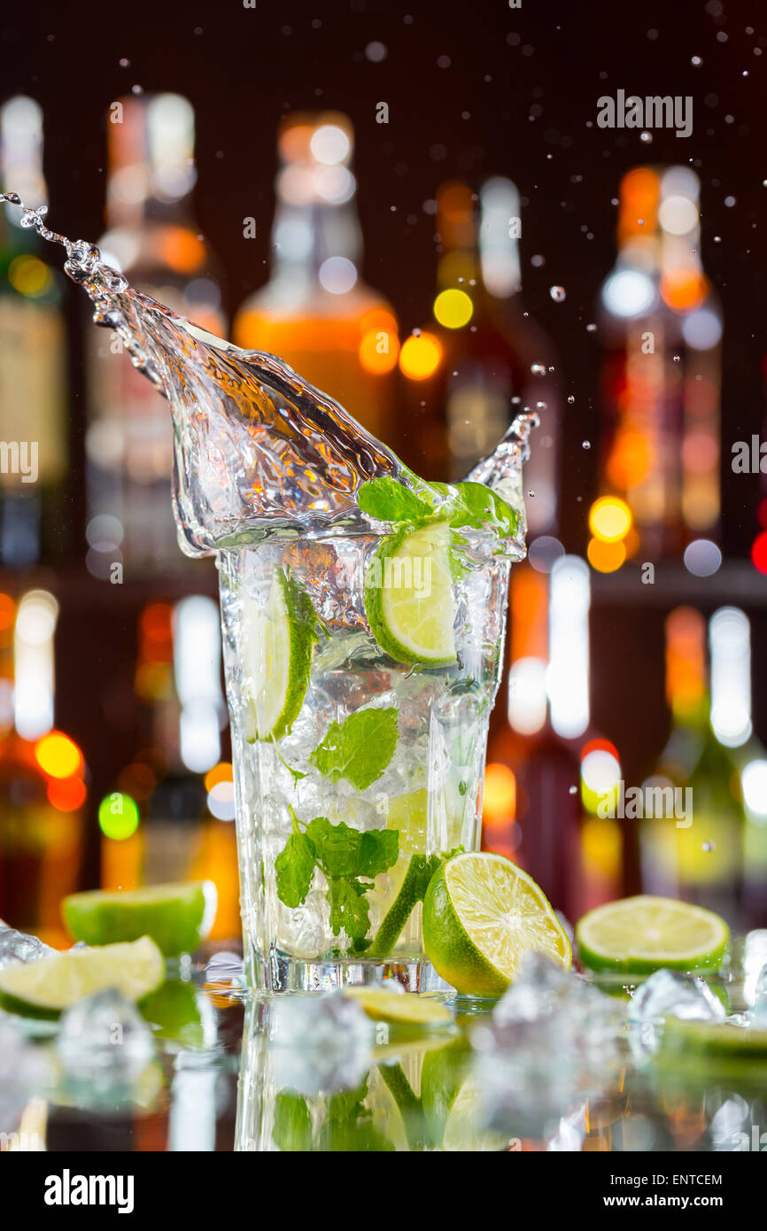 Mojito cocktail drink with splash, served on bar counter with blur ...