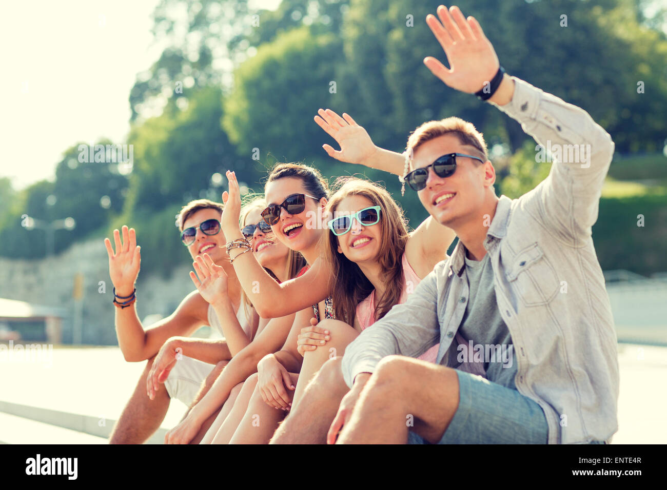 group of smiling friends sitting on city street Stock Photo - Alamy