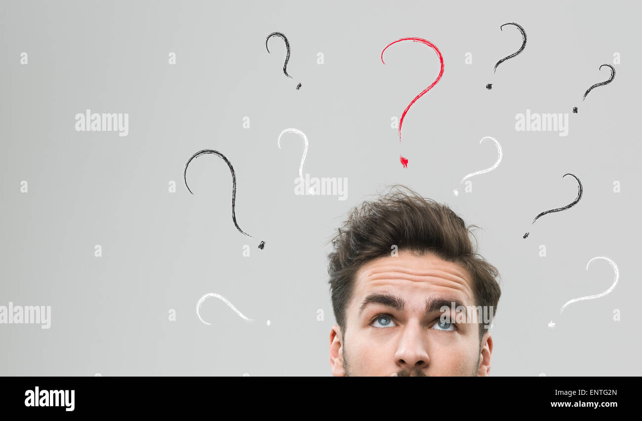 thinking man with many question marks above his head, against grey ...