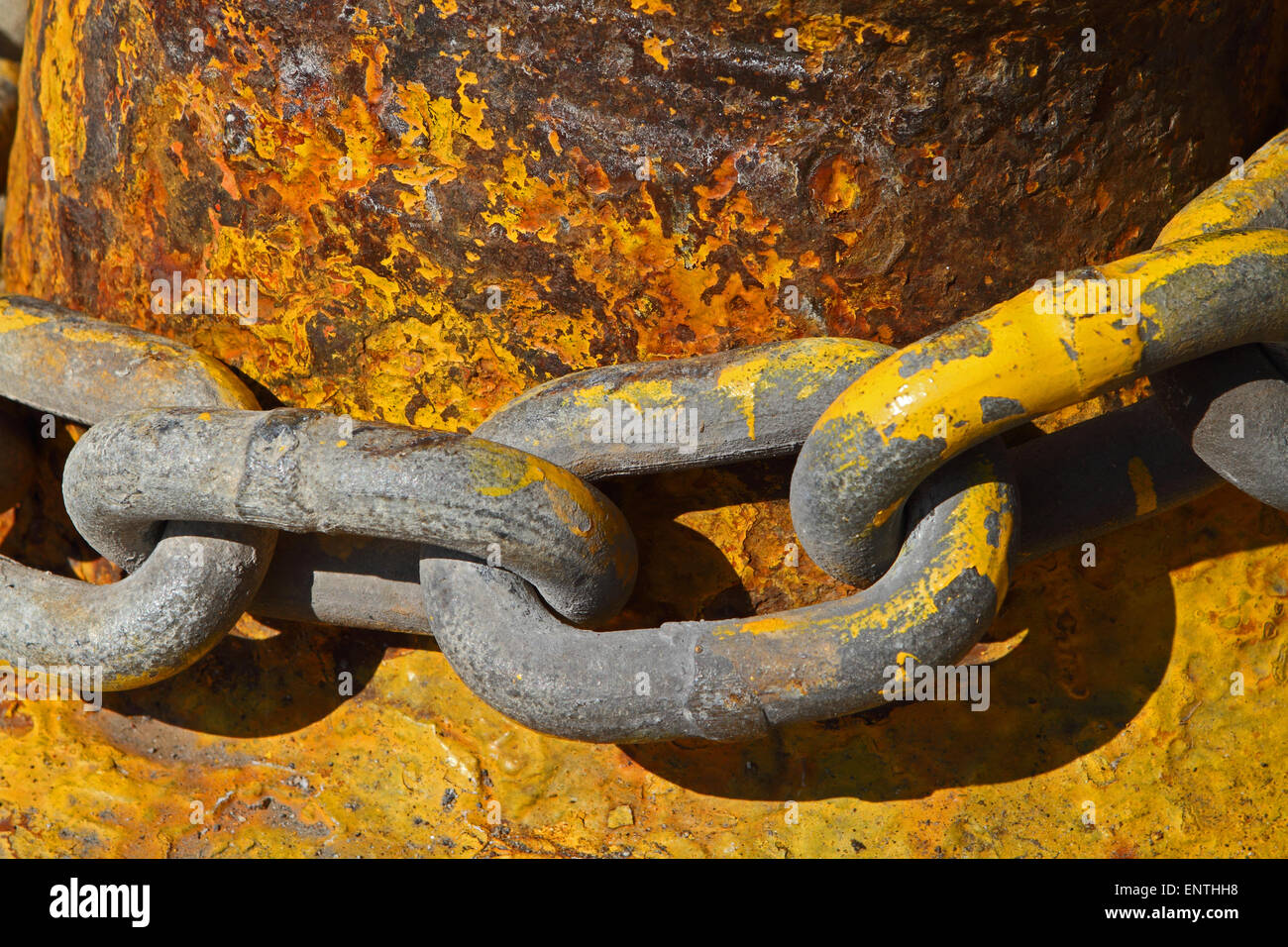 A thick metal chain wrapped round a post and covered in yellow paint ...