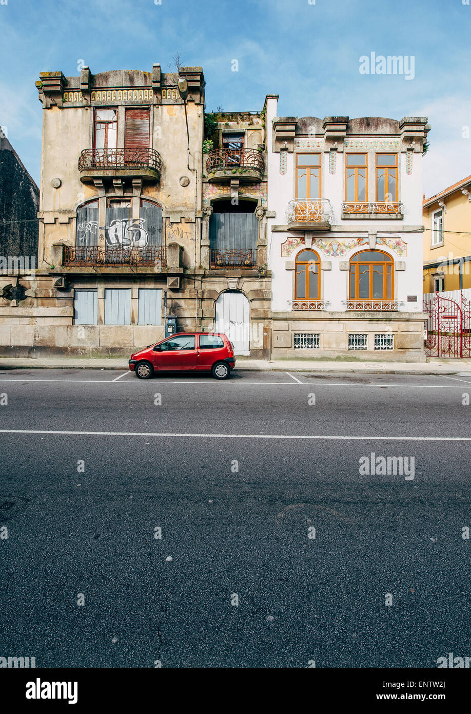 Red bright car on the street with abandoned buildings in Porto ...